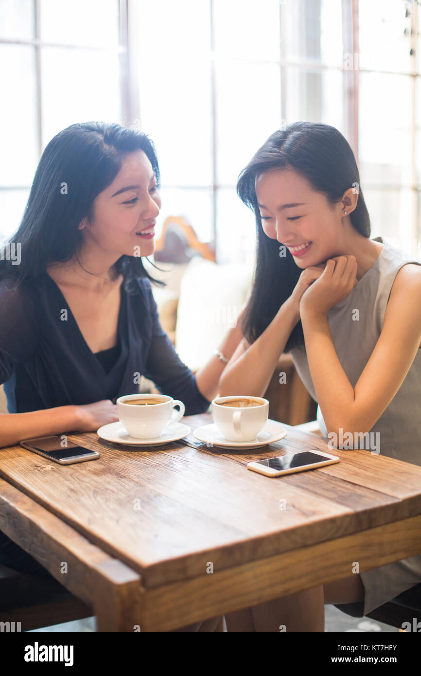 Best female friends drinking coffee in café Stock Photo - Alamy