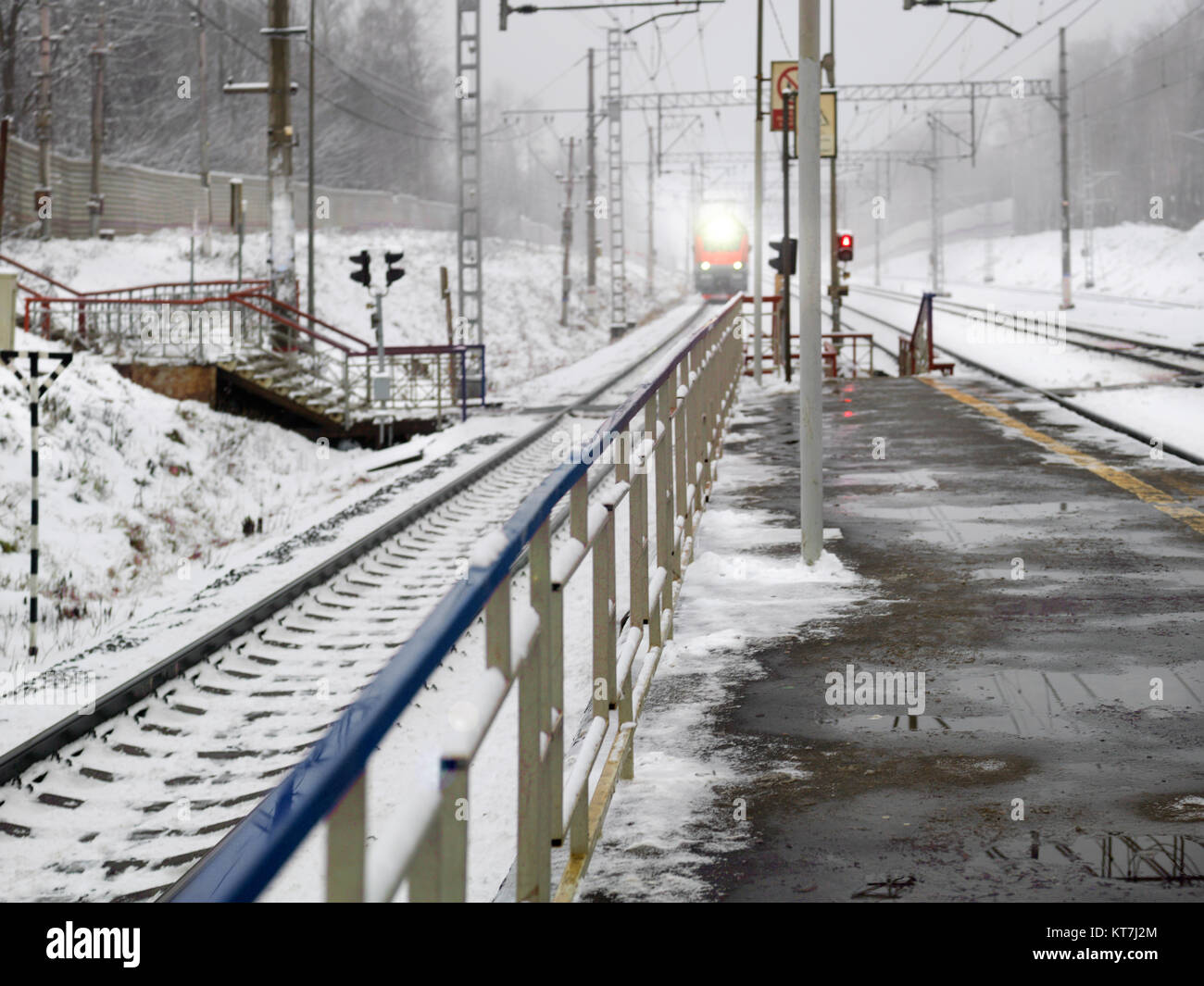 Electric railway and a train arriving, winter scene, station platform ...