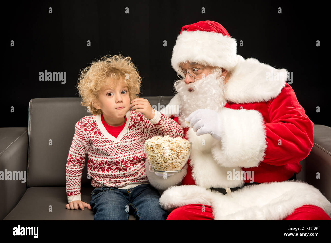 Santa Claus eating popcorn with kid Stock Photo - Alamy