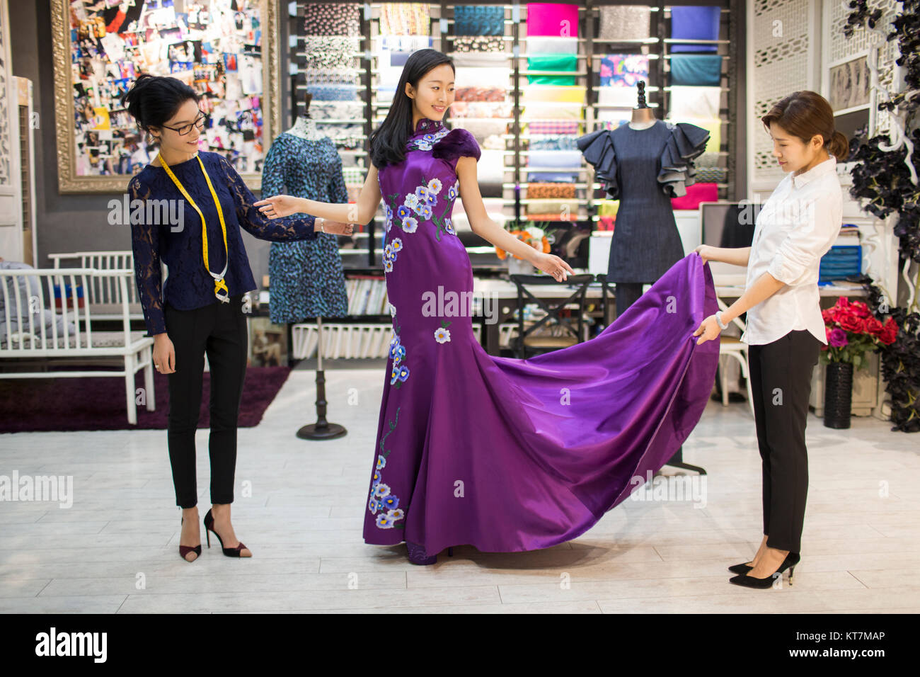 Fashion designers examining dress on customer Stock Photo - Alamy