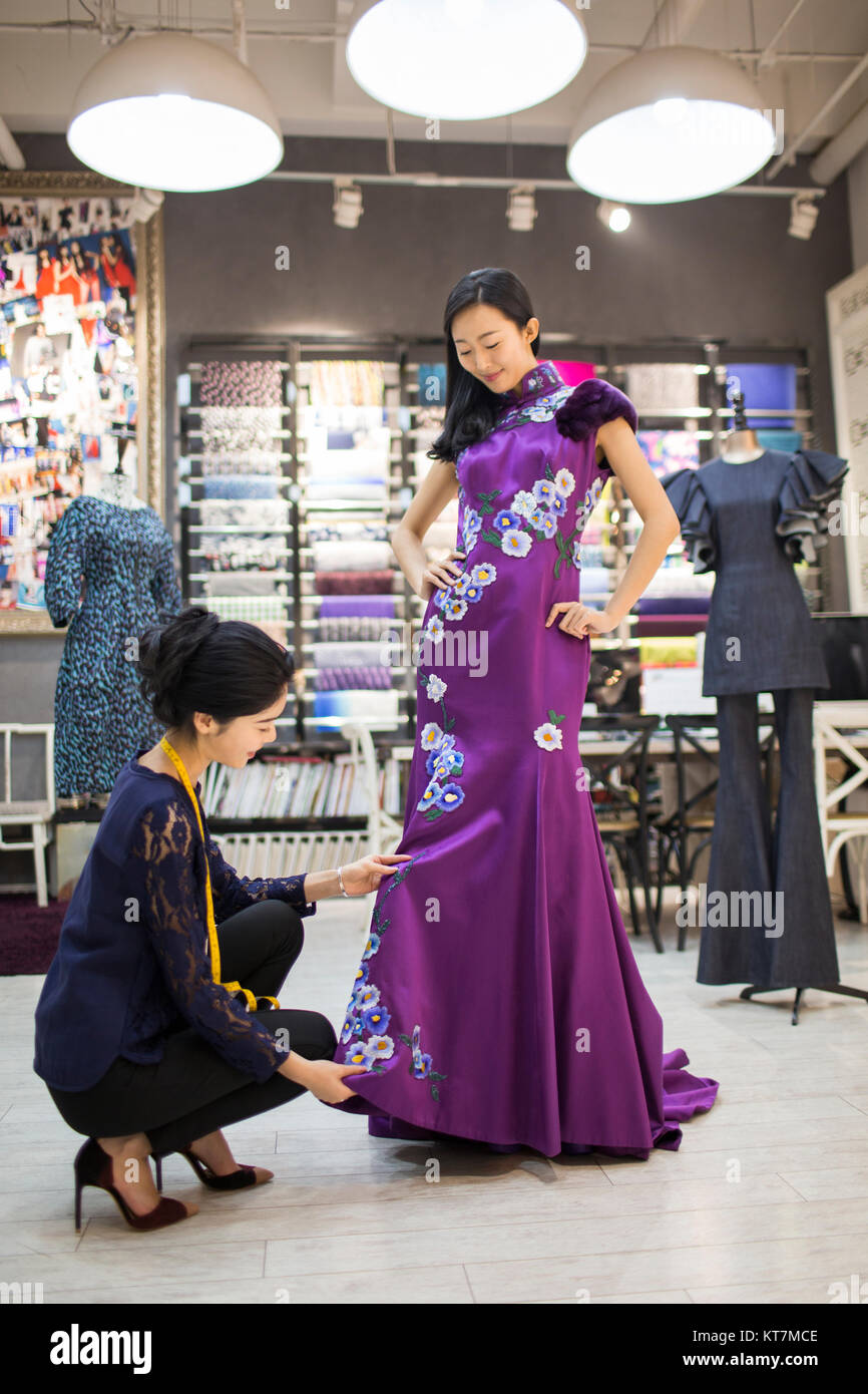 Fashion designer adjusting customer's dress Stock Photo - Alamy