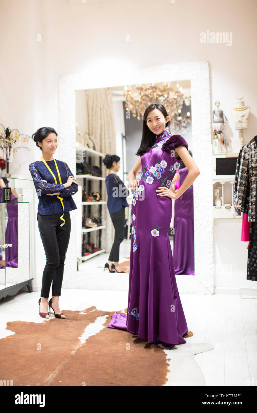 Fashion designer examining dress on customer Stock Photo - Alamy