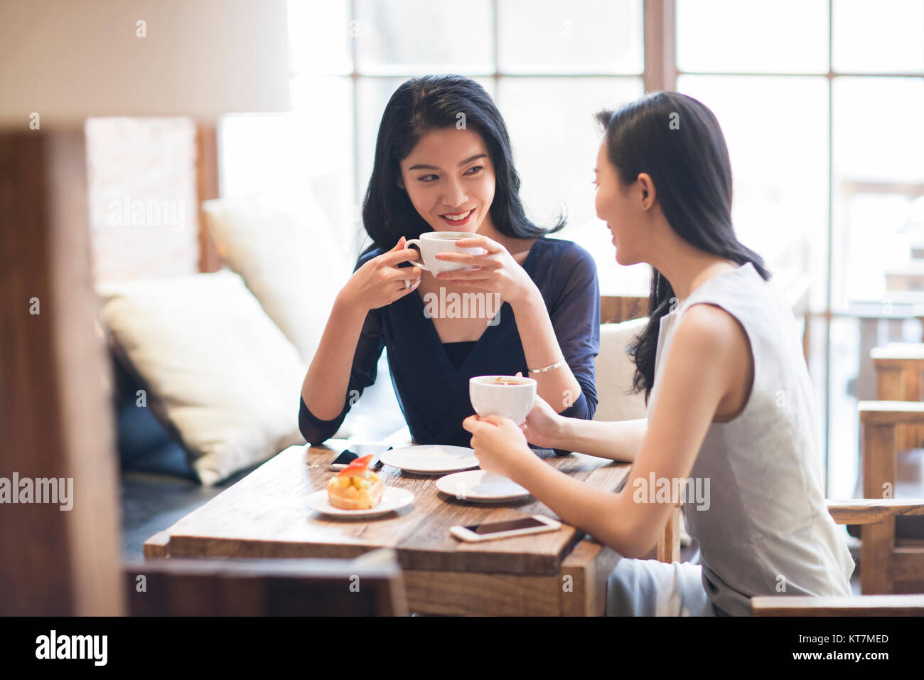 Best female friends drinking coffee in café Stock Photo - Alamy
