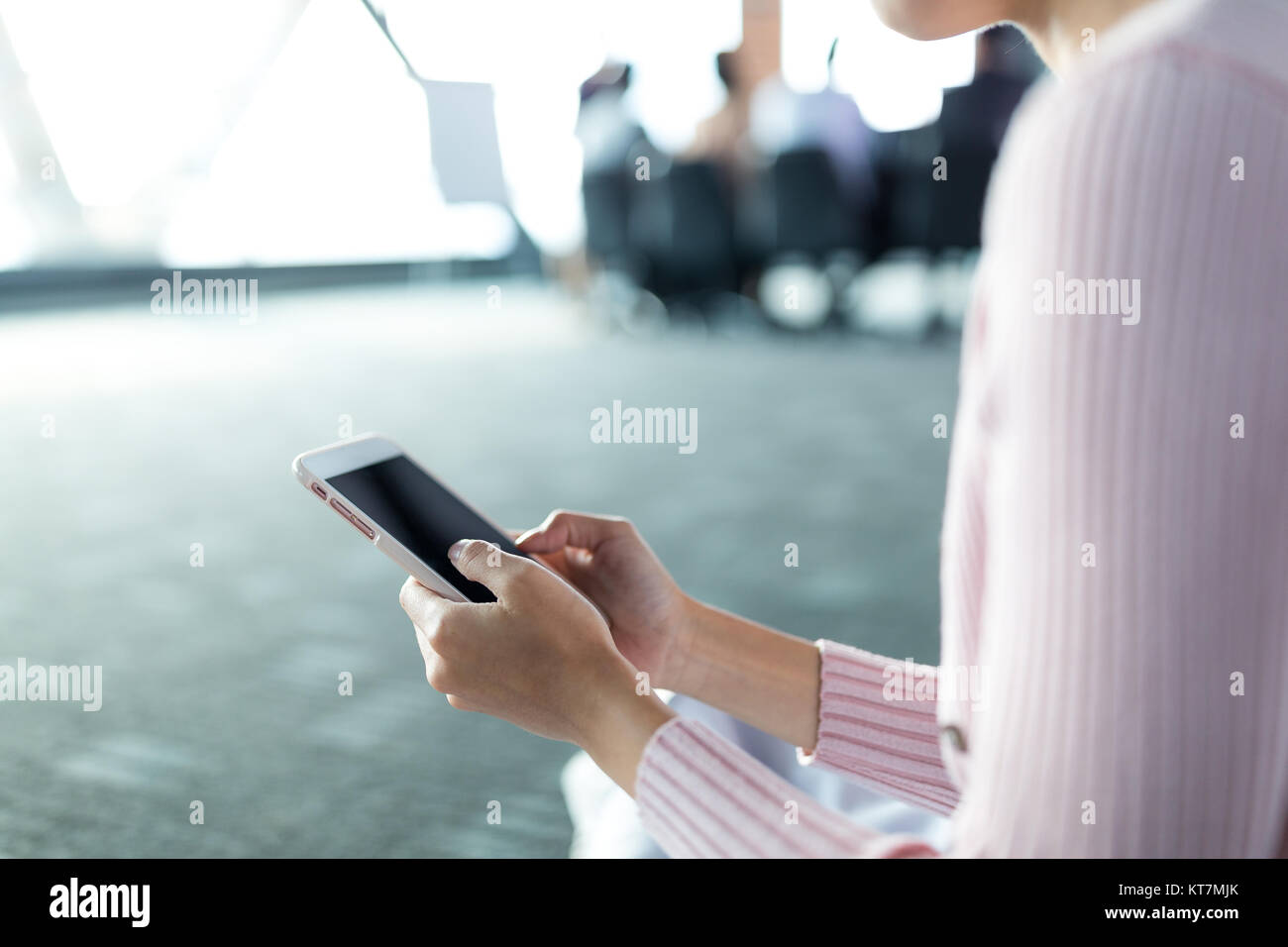 Woman using cellphone in meeting room Stock Photo - Alamy