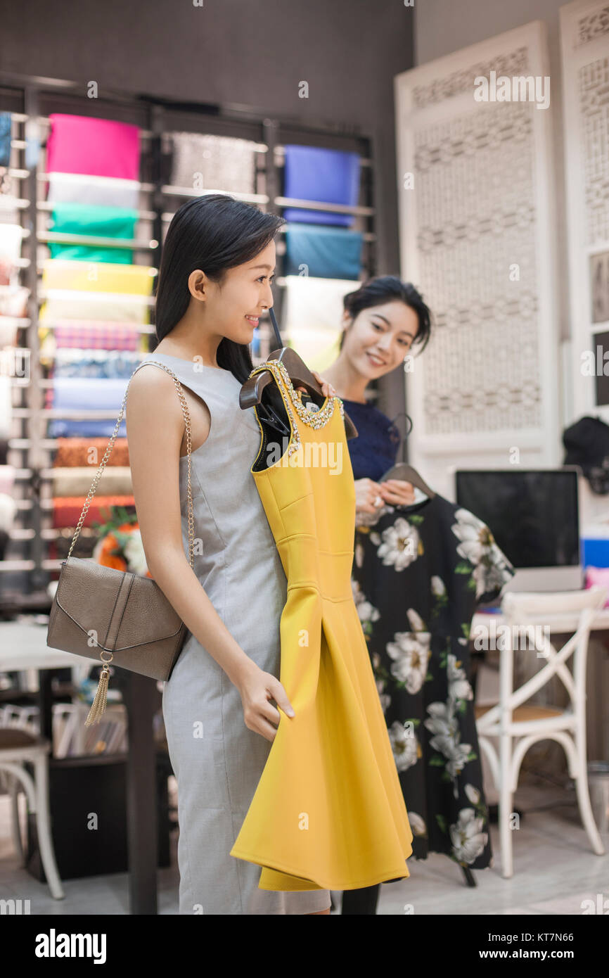 Clothing store owner helping customer choosing dress Stock Photo - Alamy