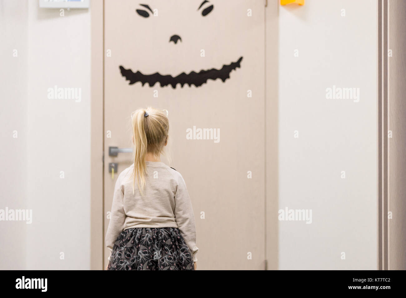 Little kid girl standing in front of doctors door and afraid to enter ...