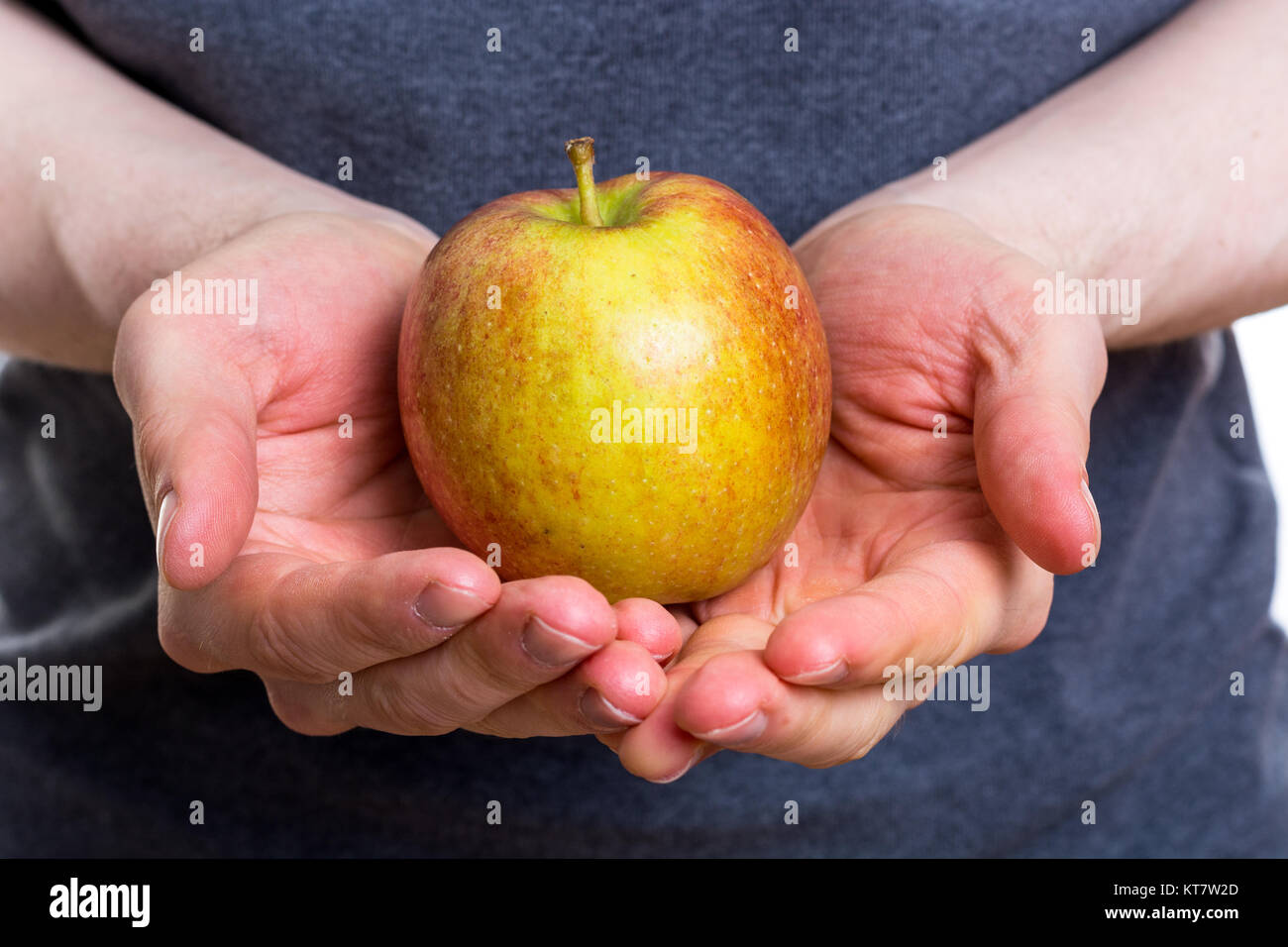 Holding an apple in both hands with a gray shirt isolated on white ...