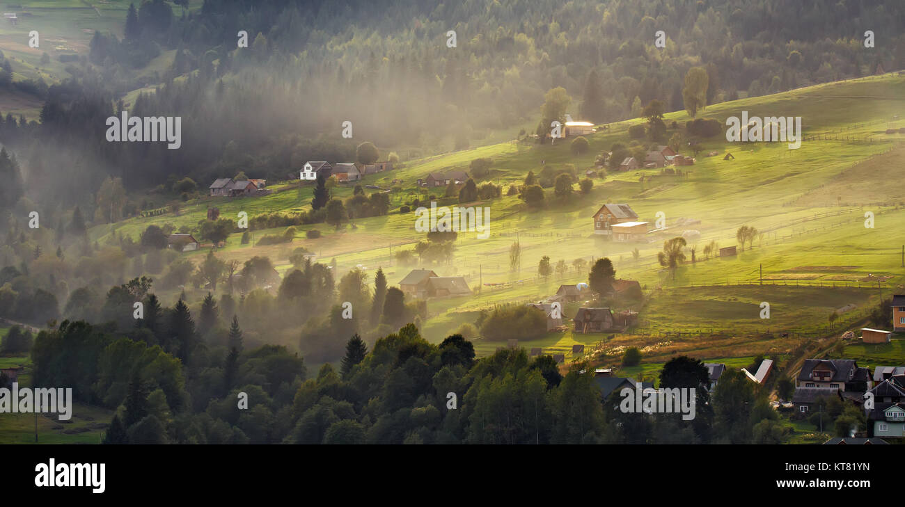 Alpine village in mountains. Smoke and haze over hills Stock Photo - Alamy