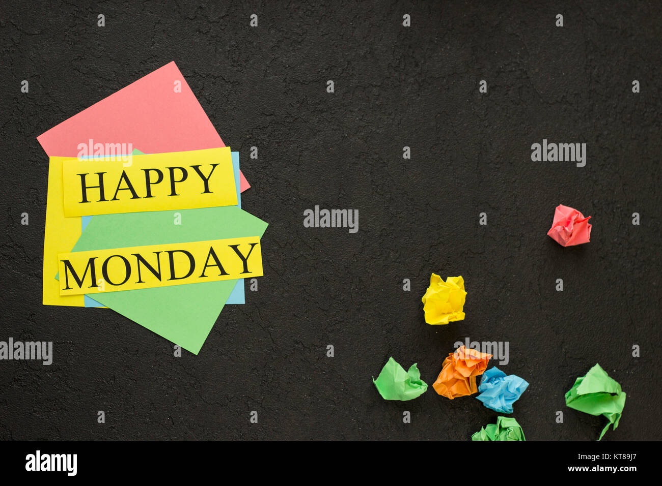 Happy monday inscription on a pile of colored note papers with balls of ...