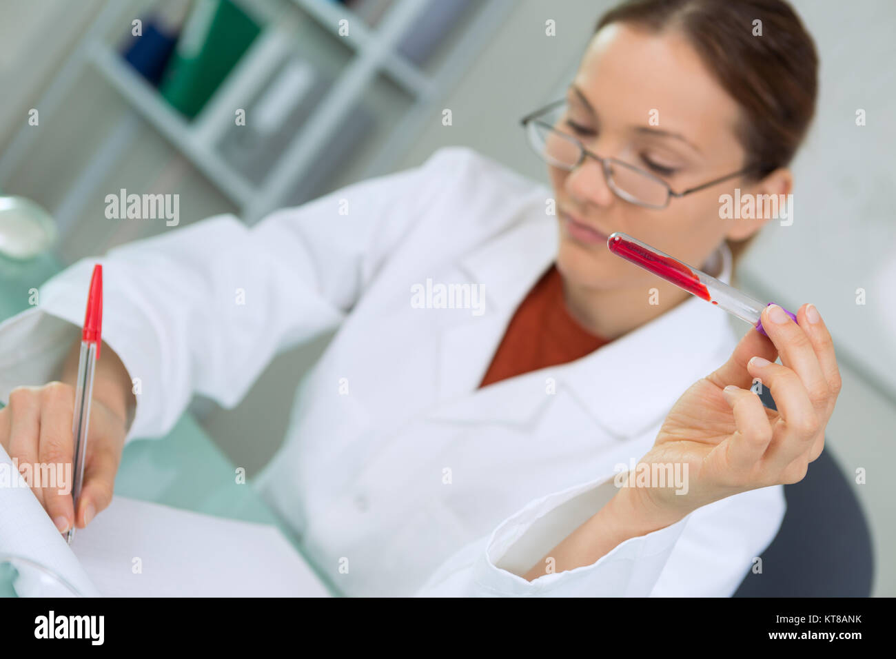 female doctor writing while holding a blood sample Stock Photo - Alamy