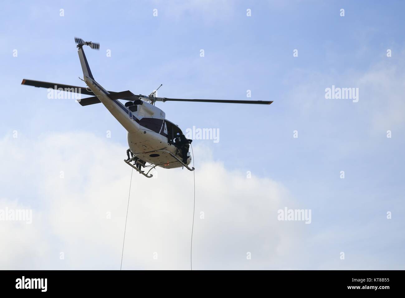 Soldier rappelling from helicopter in blue sky with blur propeller ...