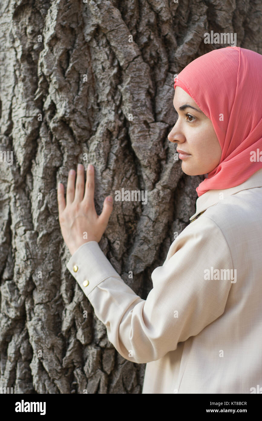 Muslim woman wearing hijab hand touching tree trunk Stock Photo - Alamy