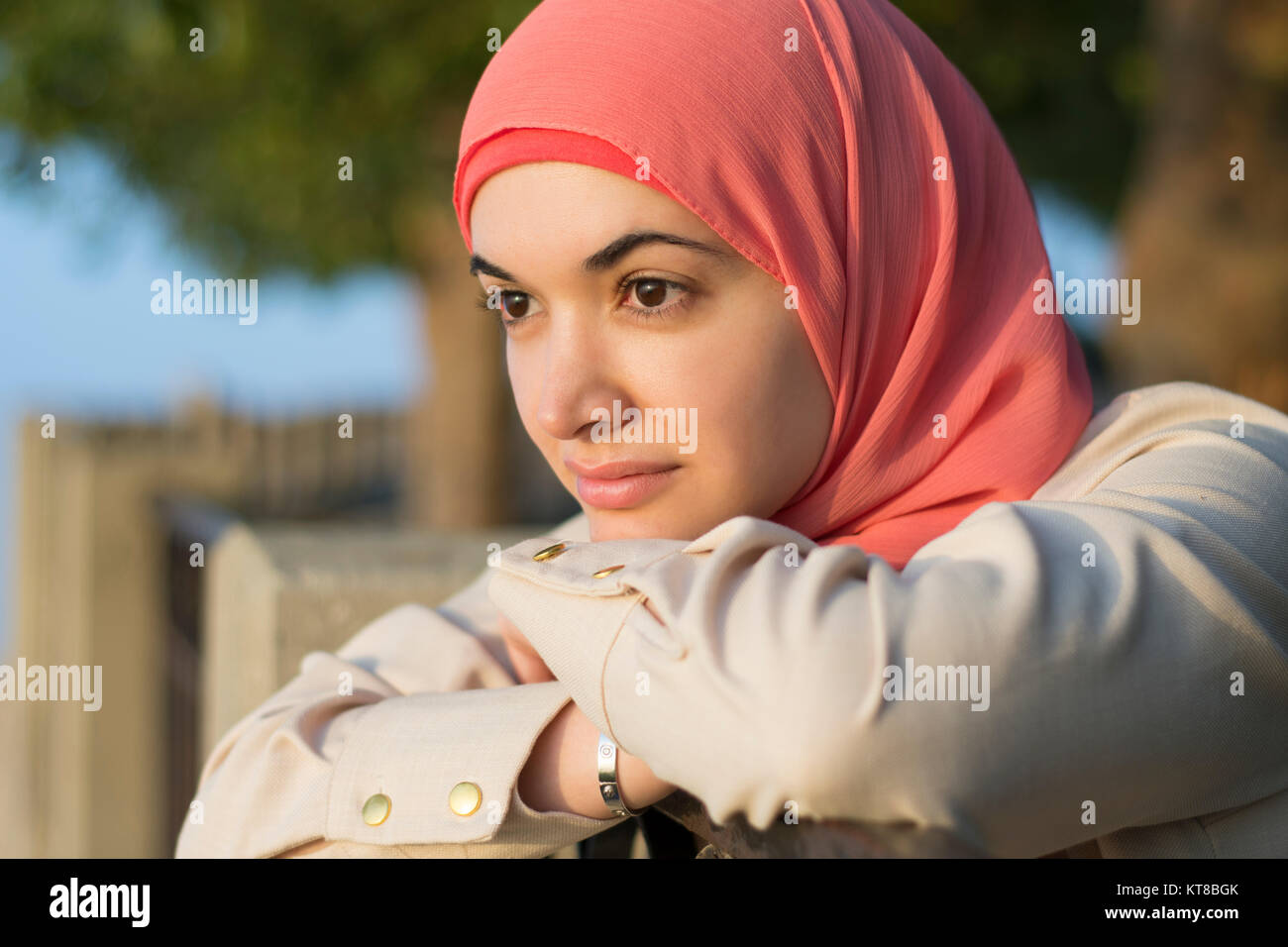 Beautiful Muslim woman leaning on the fence looking away outdoors Stock ...