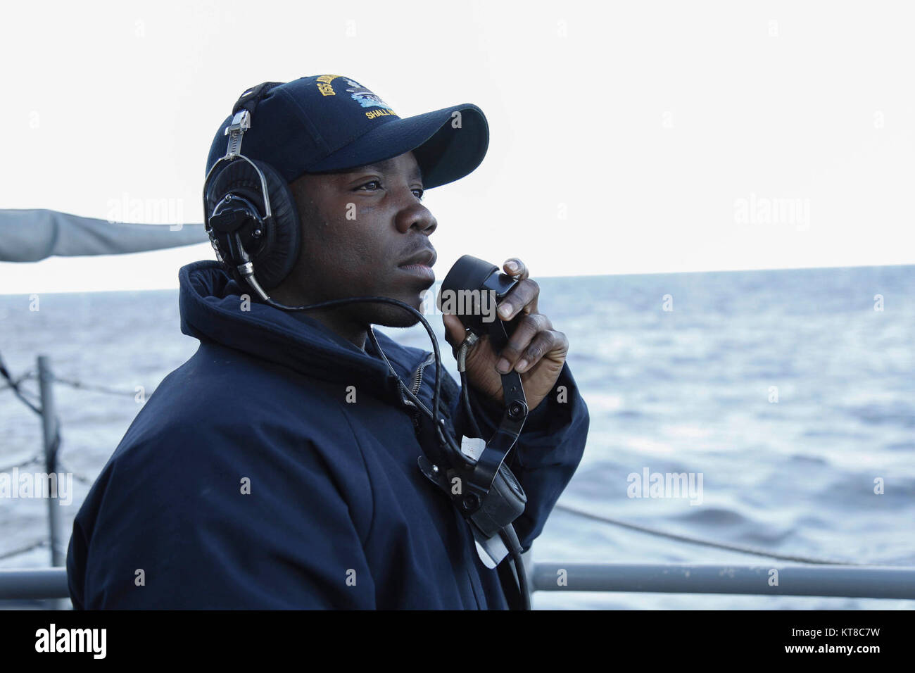 Seaman Raynard Harris uses a sound-powered telephone while standing ...