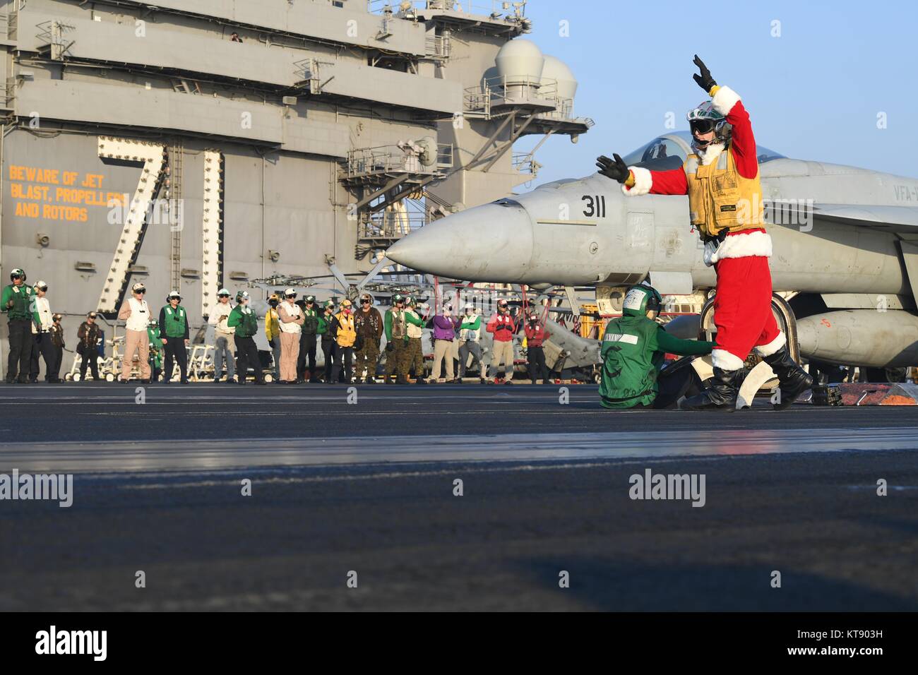 A U.S. Navy sailor dressed as Santa, signals an F/A-18 E Super Hornet ...