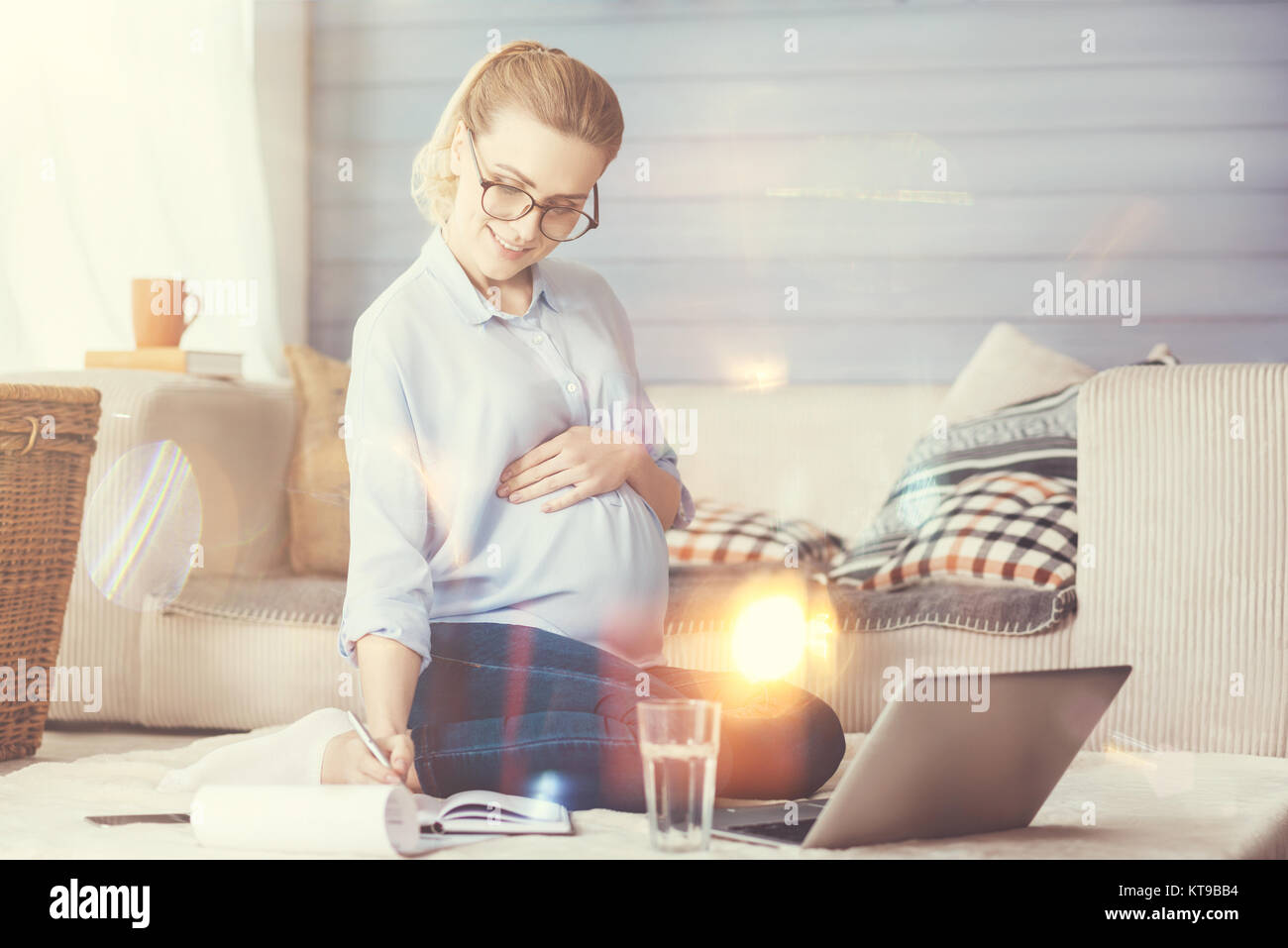 Modern lifestyle. Positive beautiful mother making notes and working at ...