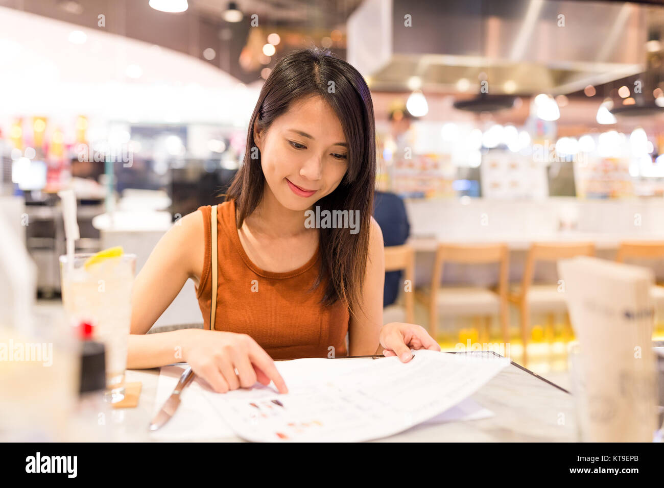 Woman looking at menu for ordering food in restaurant Stock Photo - Alamy
