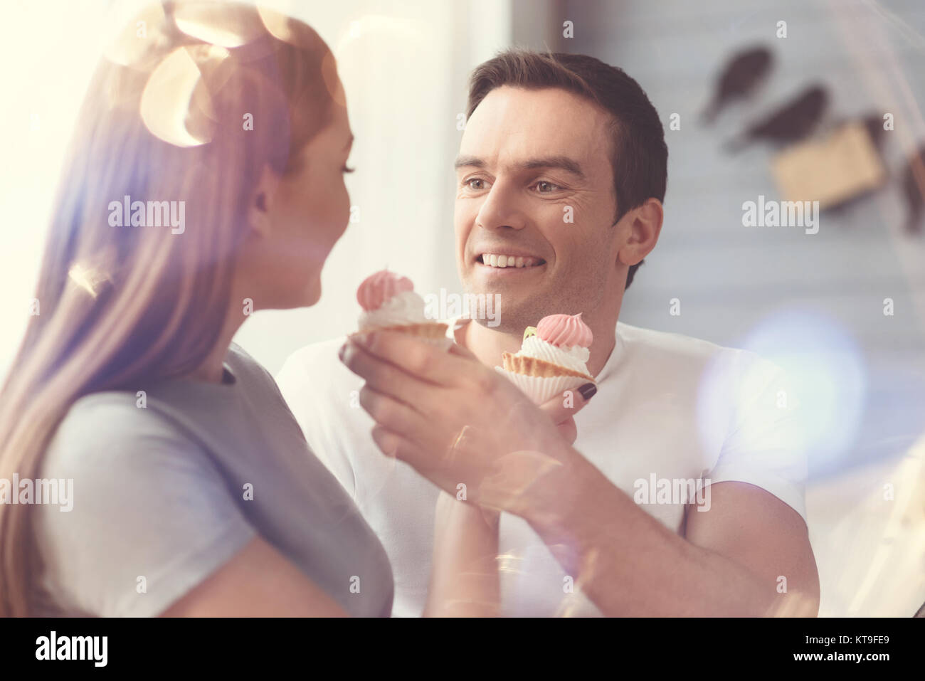 Take a bite. Two young energetic joyful people having fun feeding each ...