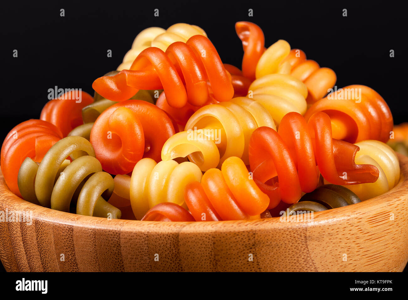 Spiral pasta trottole tricolore isolated in wooden bowl on black ...