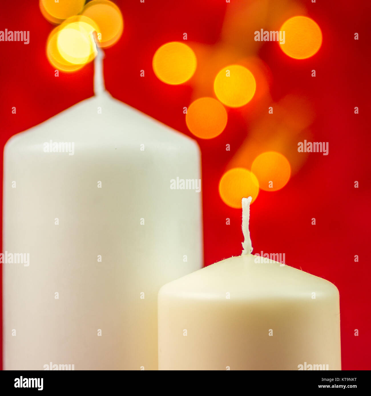Two white christmas wax candles on red background with bright yellow ...