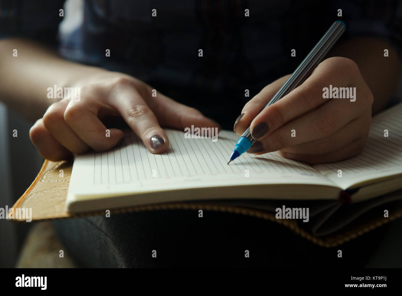 A girl is holding a notebook on her lap and writing Stock Photo - Alamy
