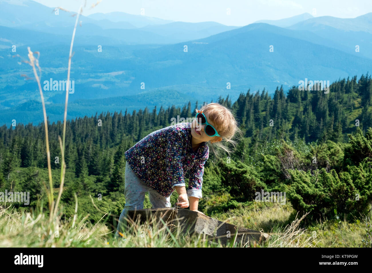 Little girl in sunglasses is scratching something on the stone. In the ...