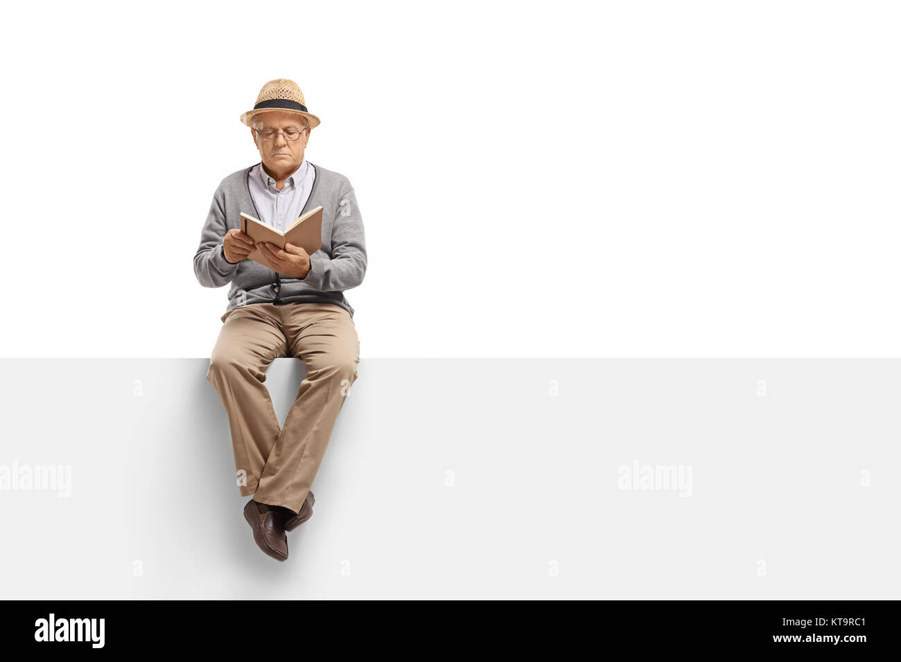 Mature man seated on a panel reading a book isolated on white ...