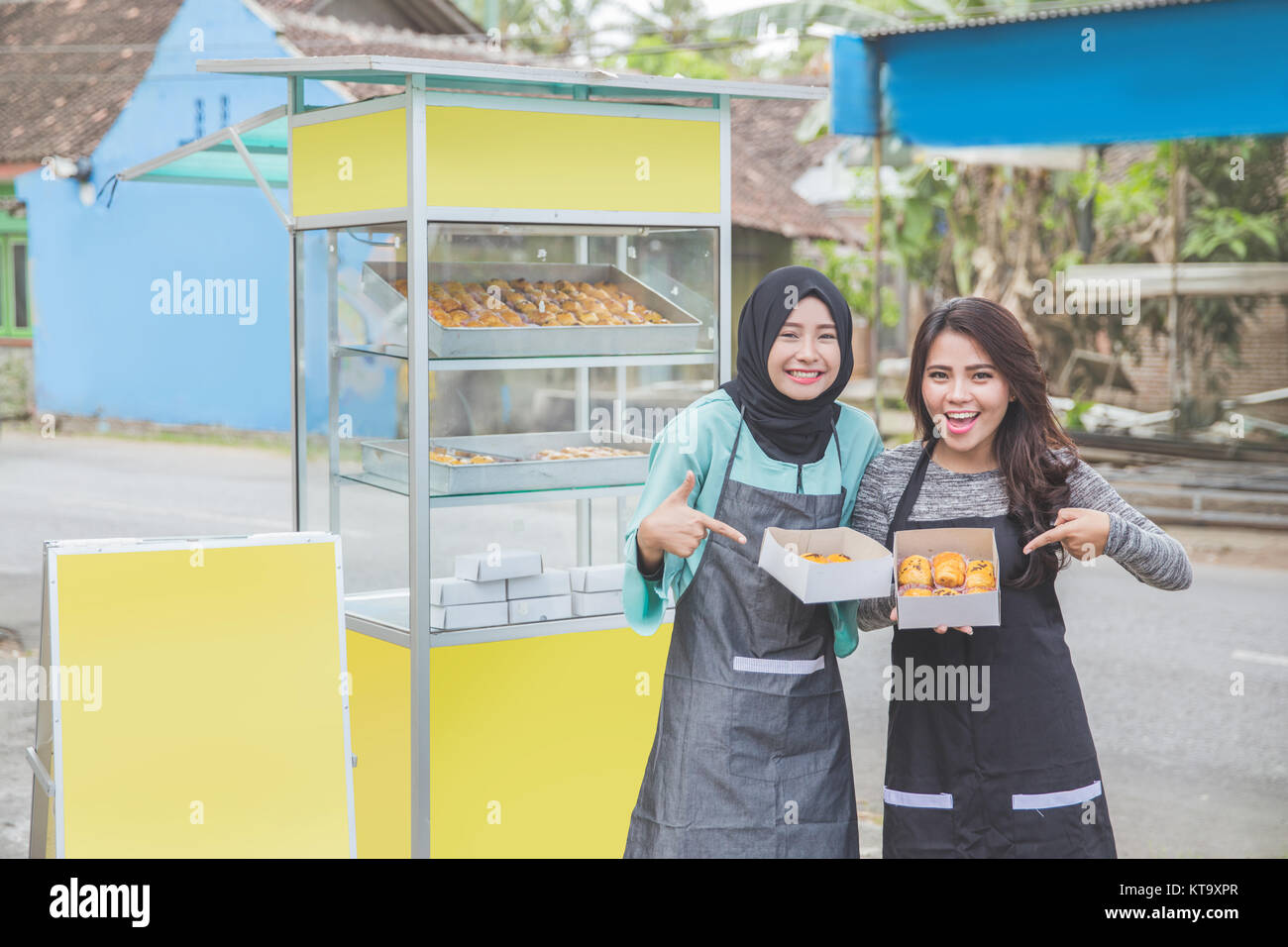 two business owner showing their fresh cake product in the food stall ...