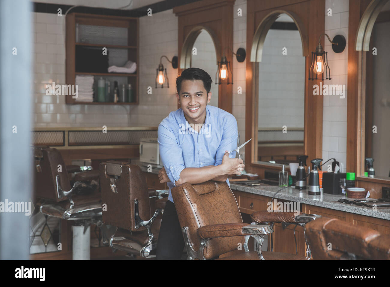 Confident barber expert. Young man looking at camera and smiling ... Confident barber expert. Young man looking at camera and smiling ...