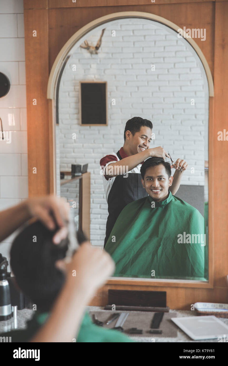 portrait of Young handsome barber making haircut of attractive man in ...