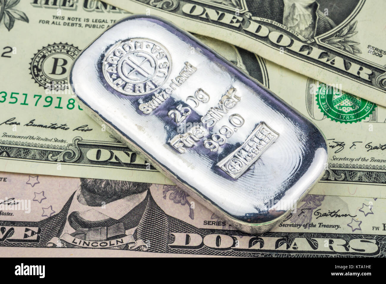 silver brick laying on dollar banknotes Stock Photo - Alamy