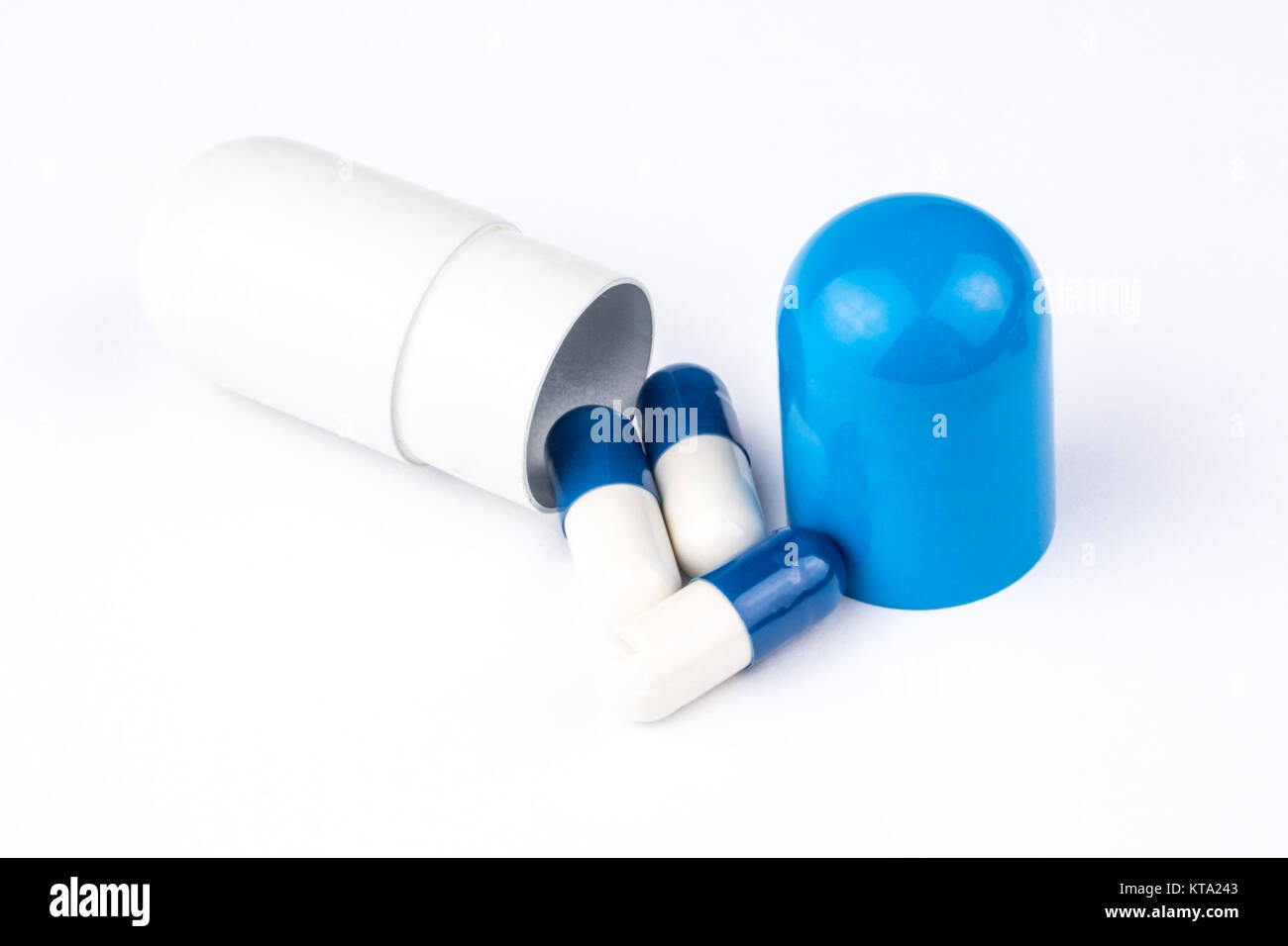 three small pills are coming out from big blue and white capsule ...