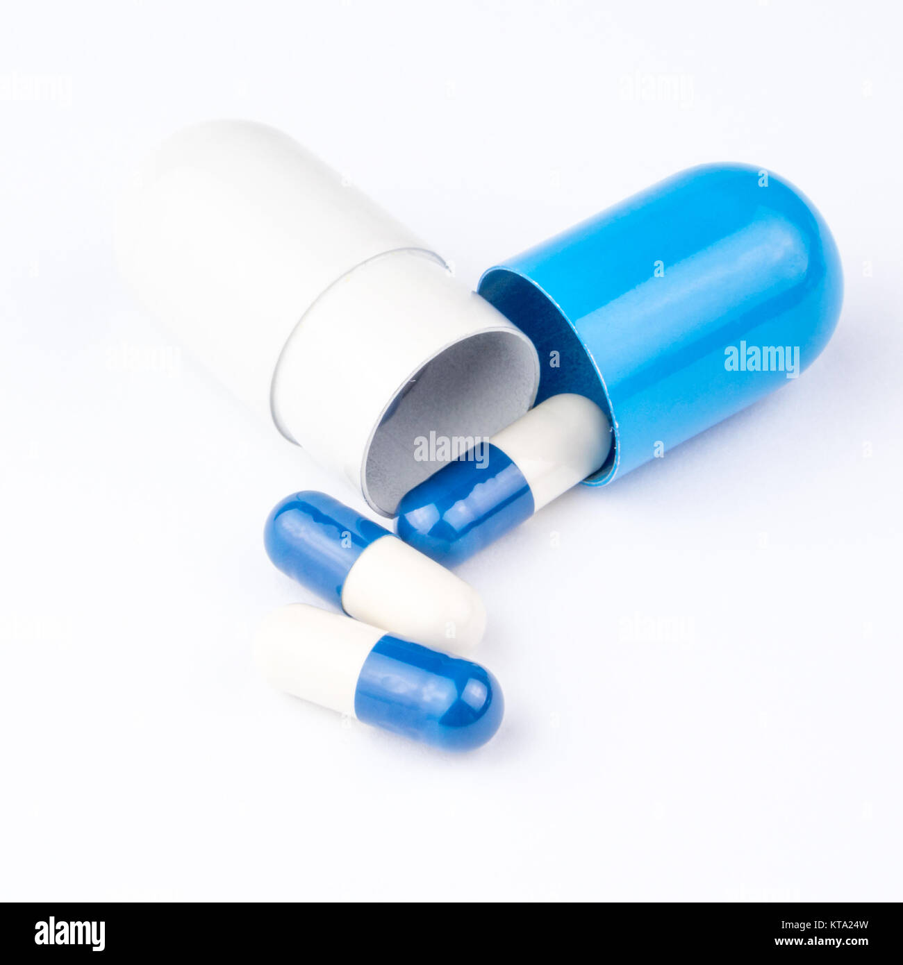 three small pills are coming out from big blue and white capsule ...