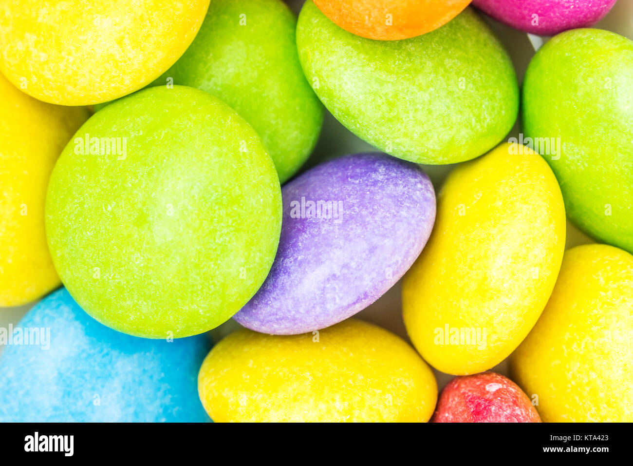 closeup of multicolored sweet choco lentils scattered on white ...