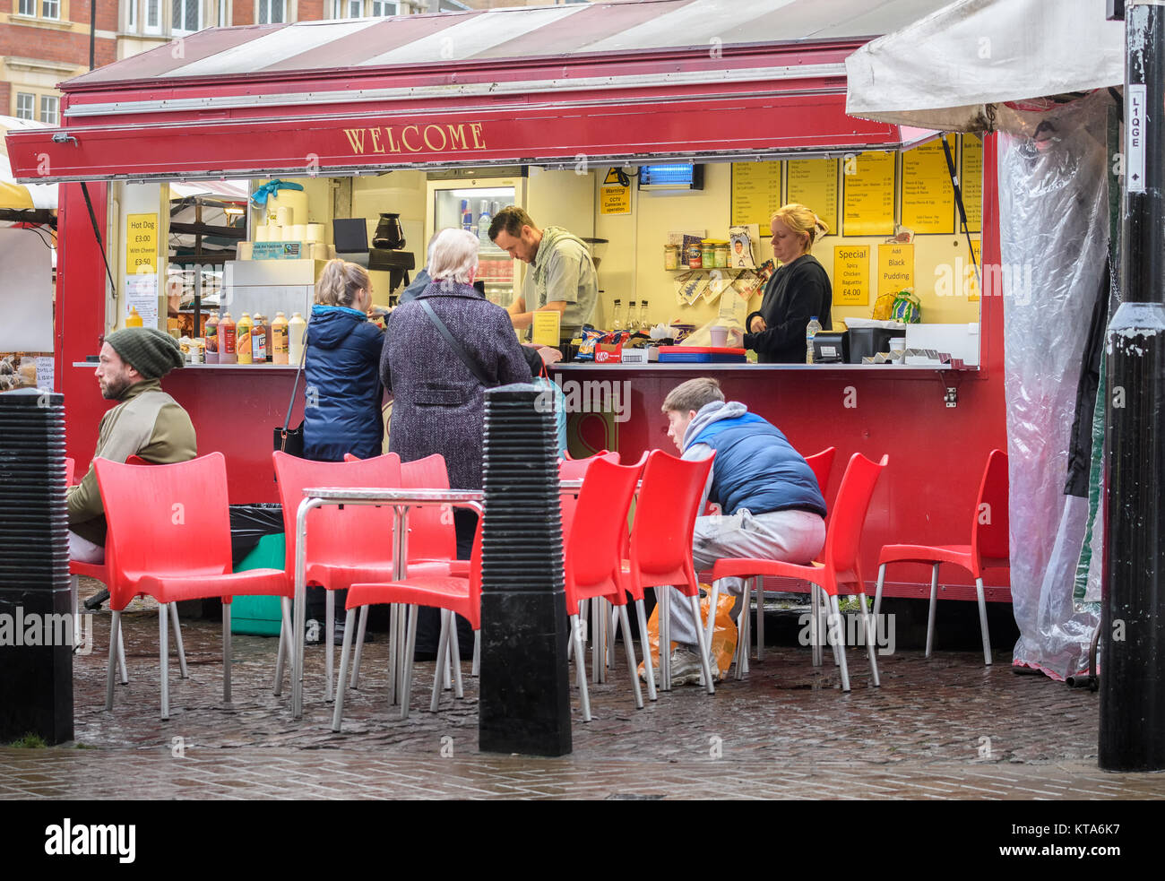 Customer and staff at a mobile cafe stall on a rainy winter day in the ...