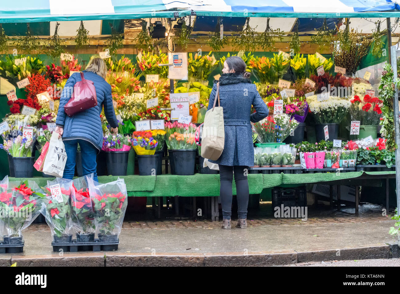 Two female customers at a florist stall on a rainy winter day in the ...