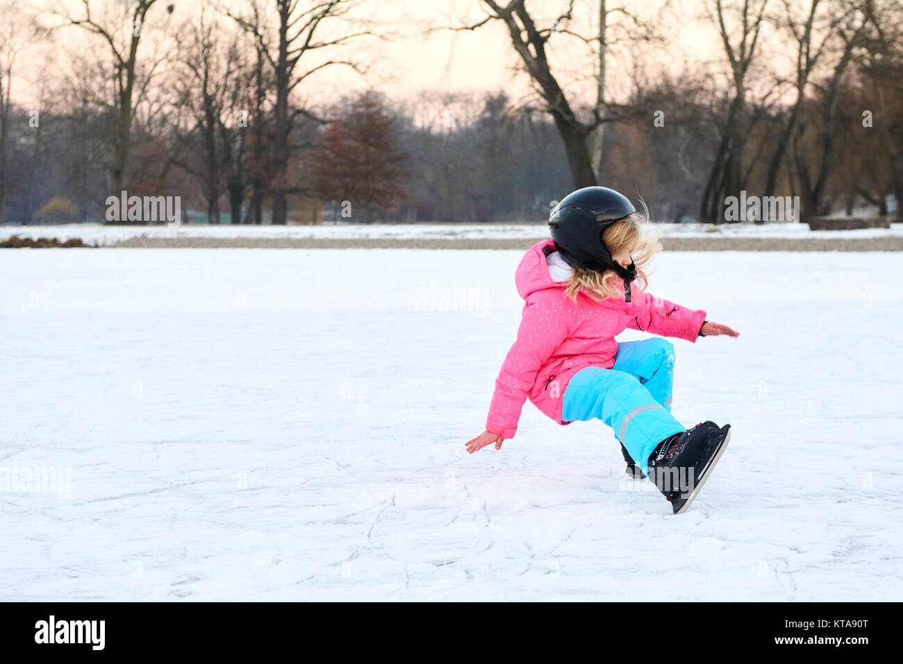 Child girl falling down on ice in snowy park during winter holidays ...
