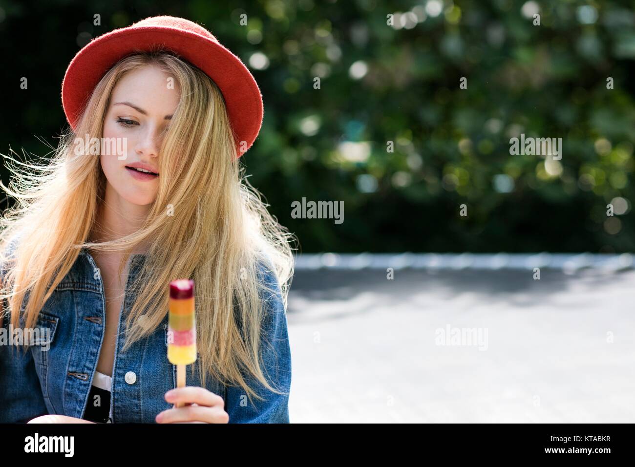 Young woman in red hat eating ice lolly Stock Photo - Alamy