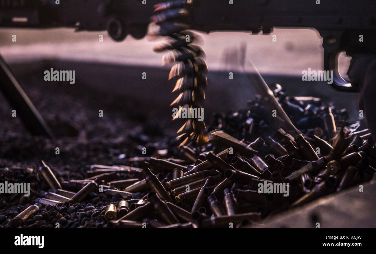 Shell casing fall to the ground as rounds are fired out of an M-249 ...