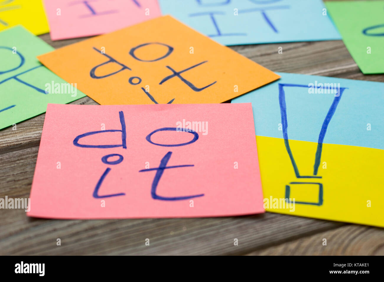 Colorful note papers inscribed with do it words, close up. Light wooden ...