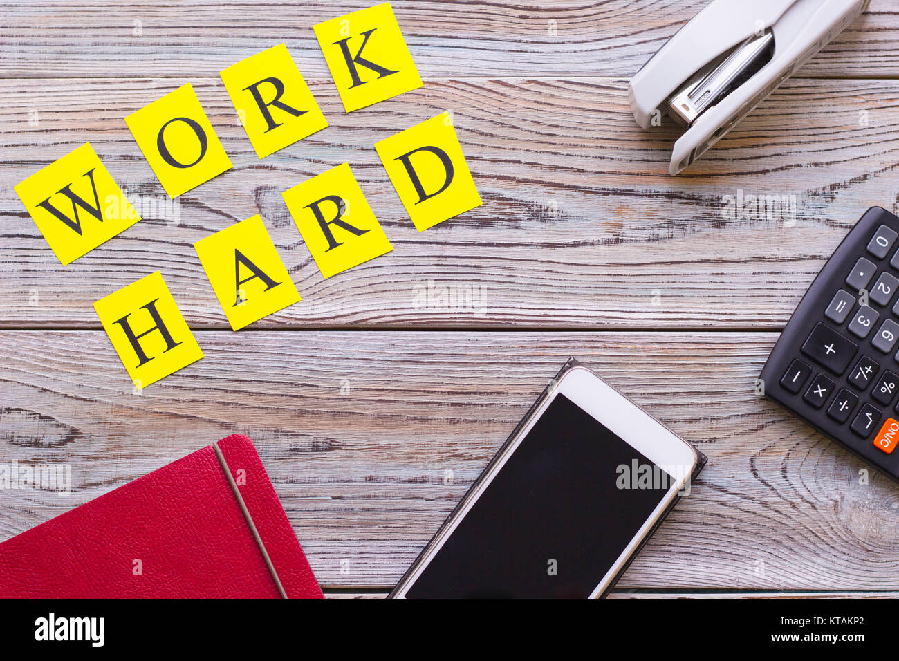 Work hard printed inscription with office items on a light wooden table ...