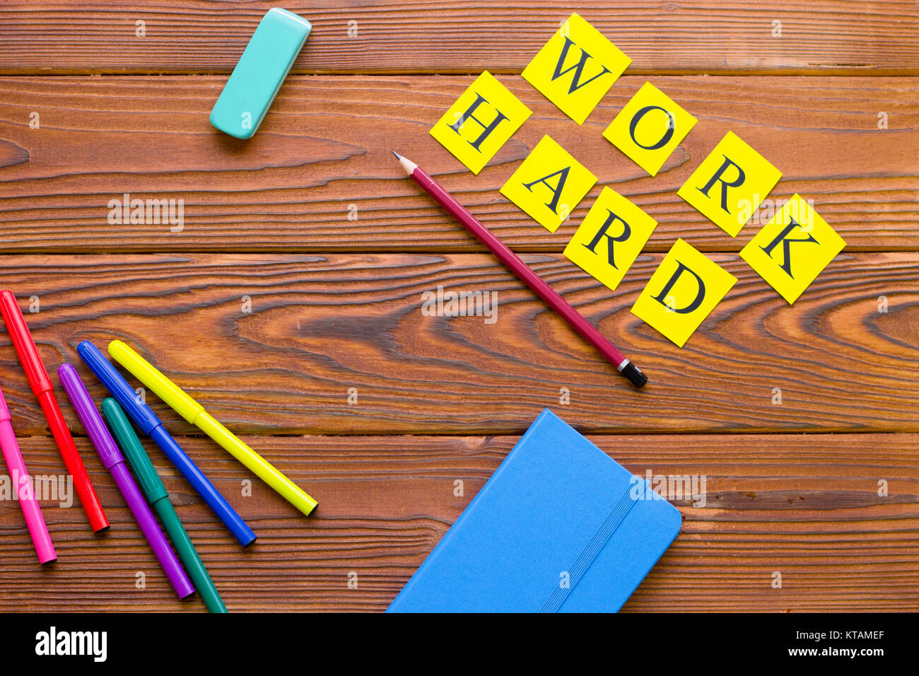 Work hard printed inscription with colored markers and notebook on a ...