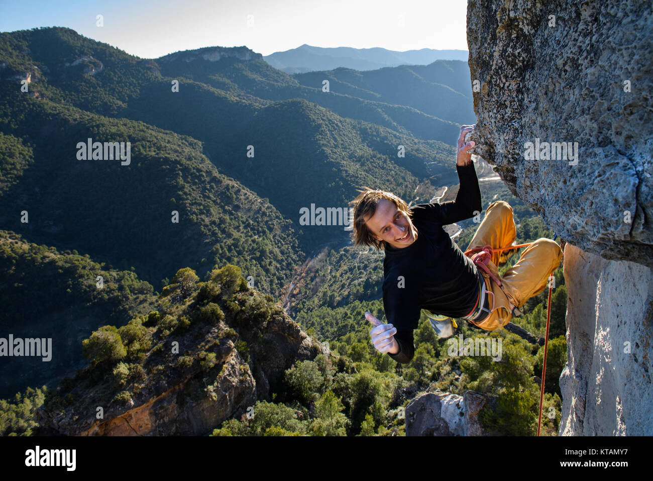 Happy rock climber ascending a challenging cliff. Extreme sport ...