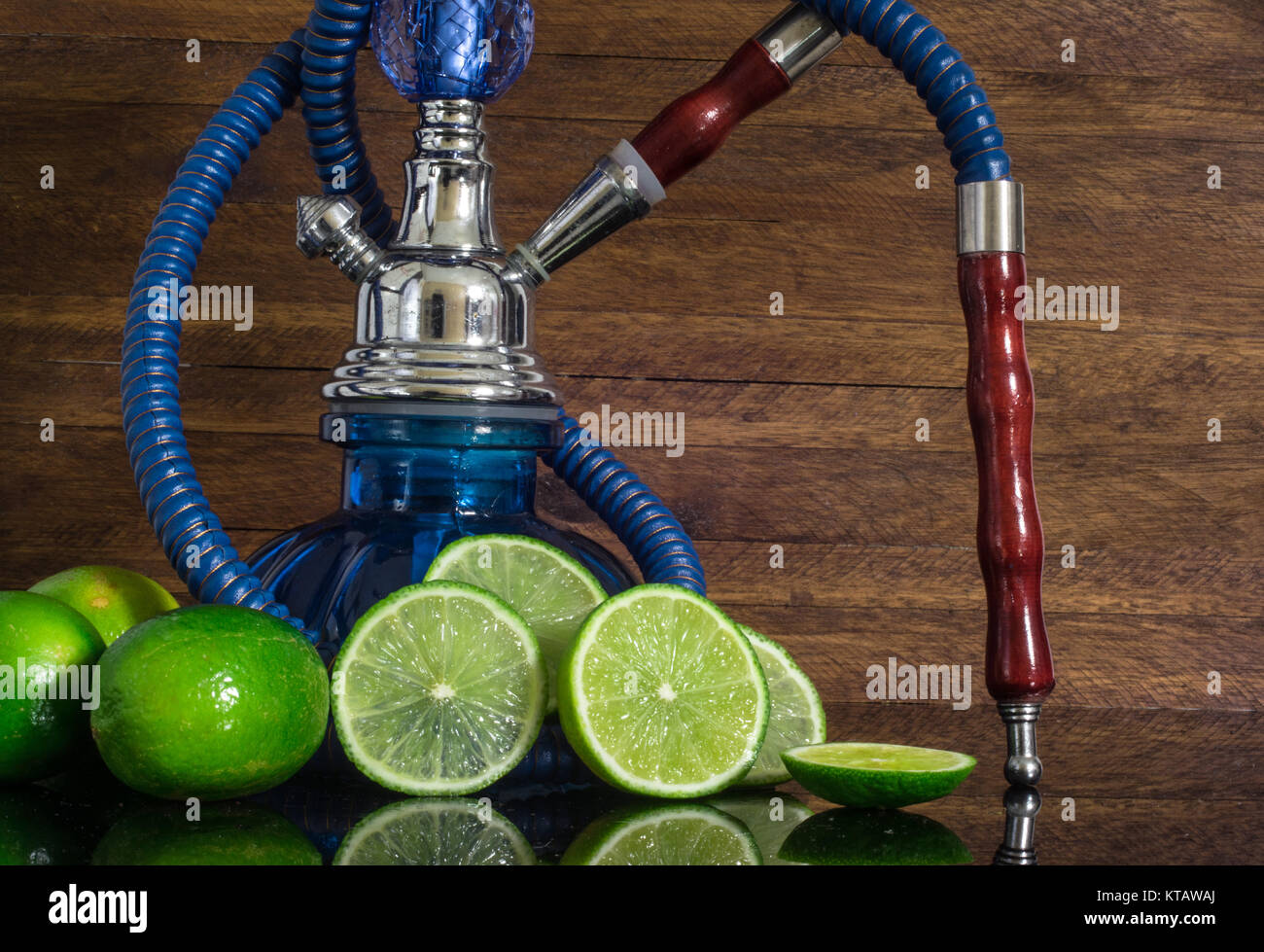 Hookah on top of a reflective surface, with lemons and lime, wooden ...