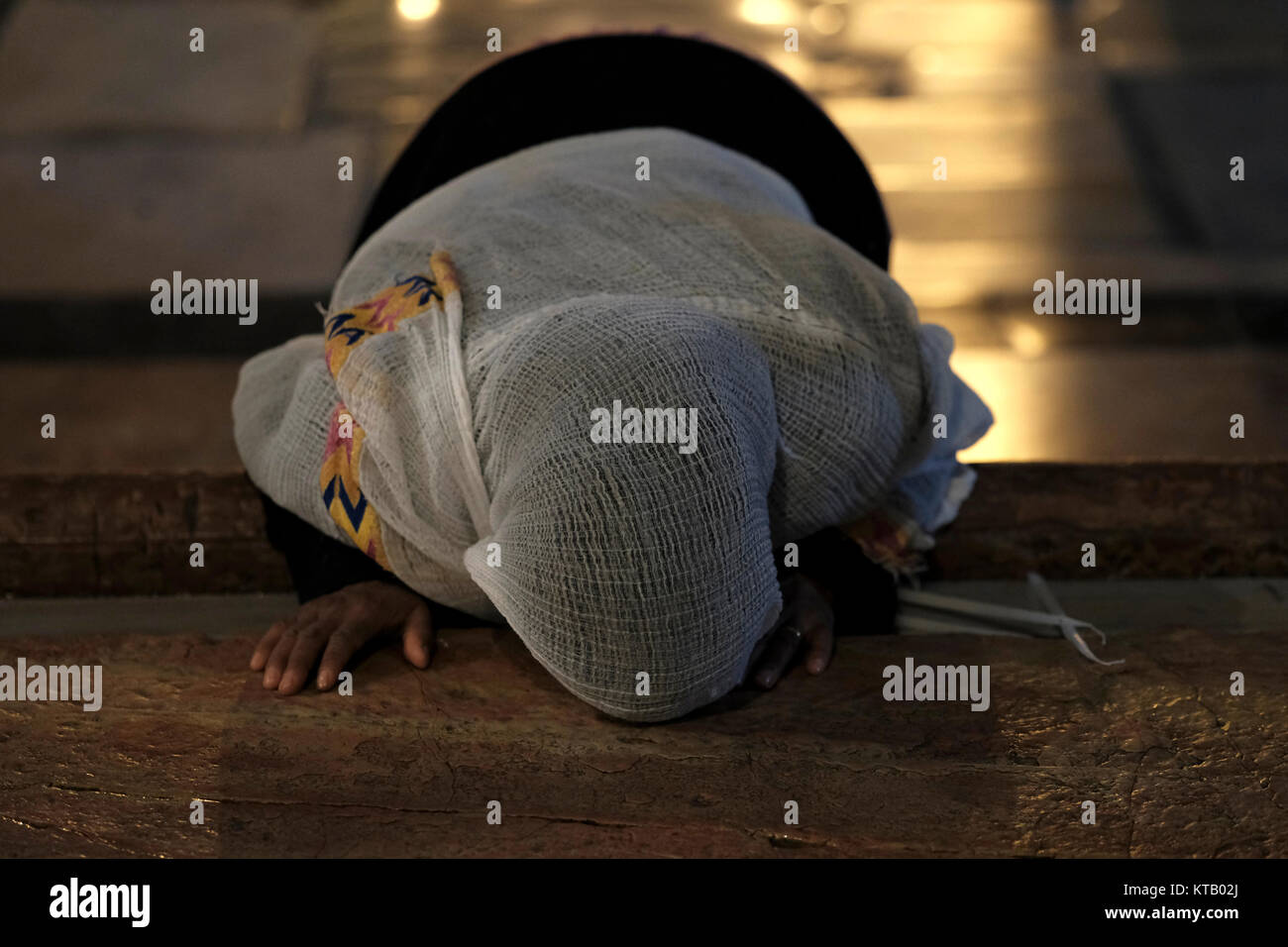 Ethiopian Orthodox worshiper praying over the Stone of the Anointing or ...