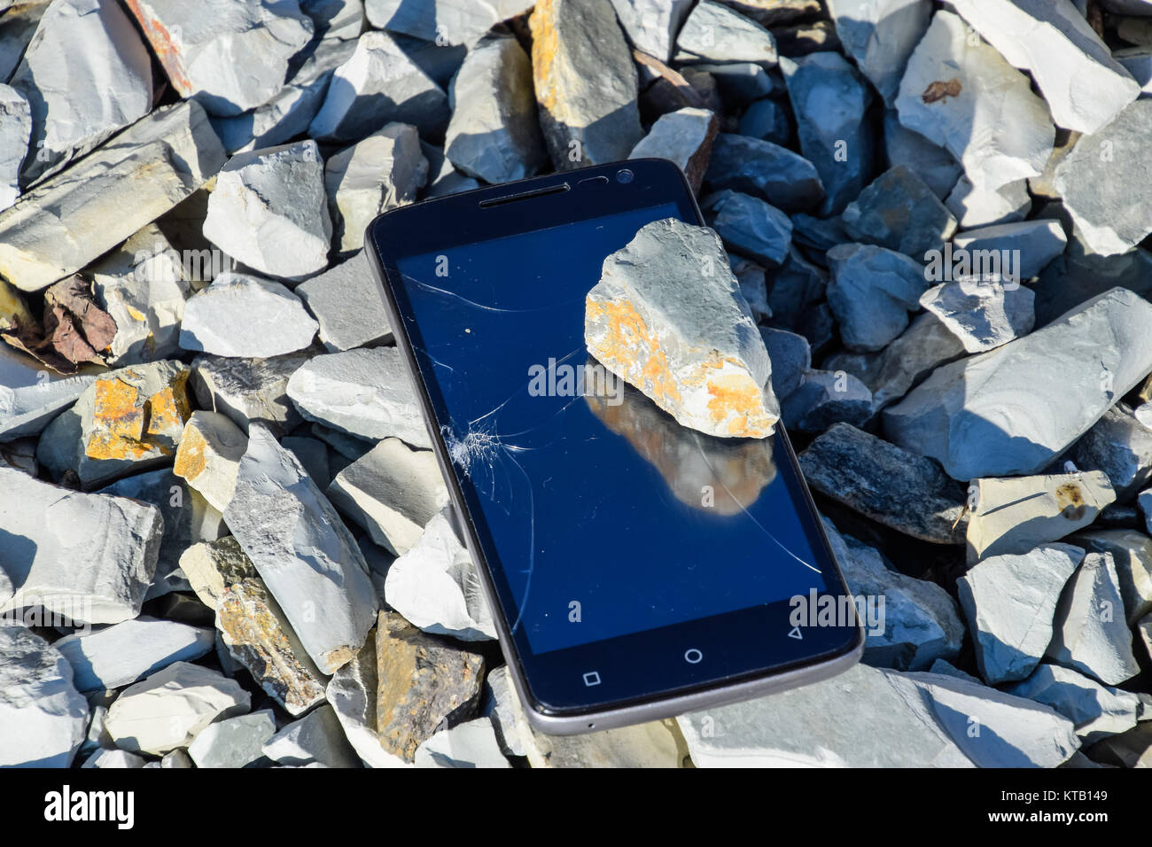 Frustrated phone on the rocks. Glass shattered on rocks on a sma Stock ...
