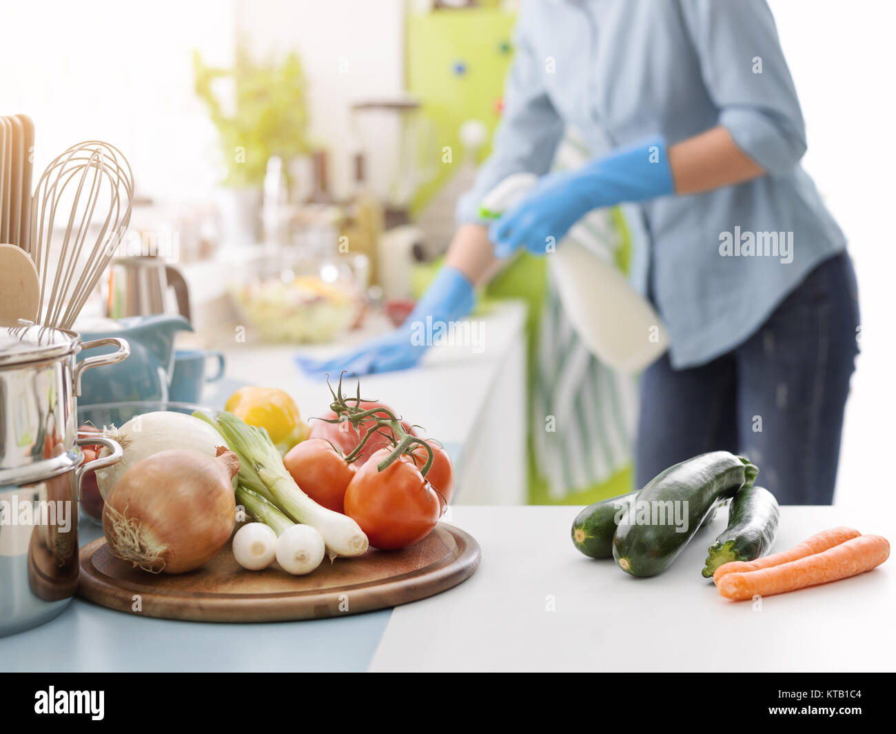 Woman cleaning and polishing the kitchen worktop with a spray detergent ...
