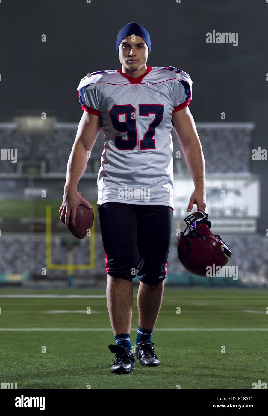 portrait of young confident American football player walking through ...