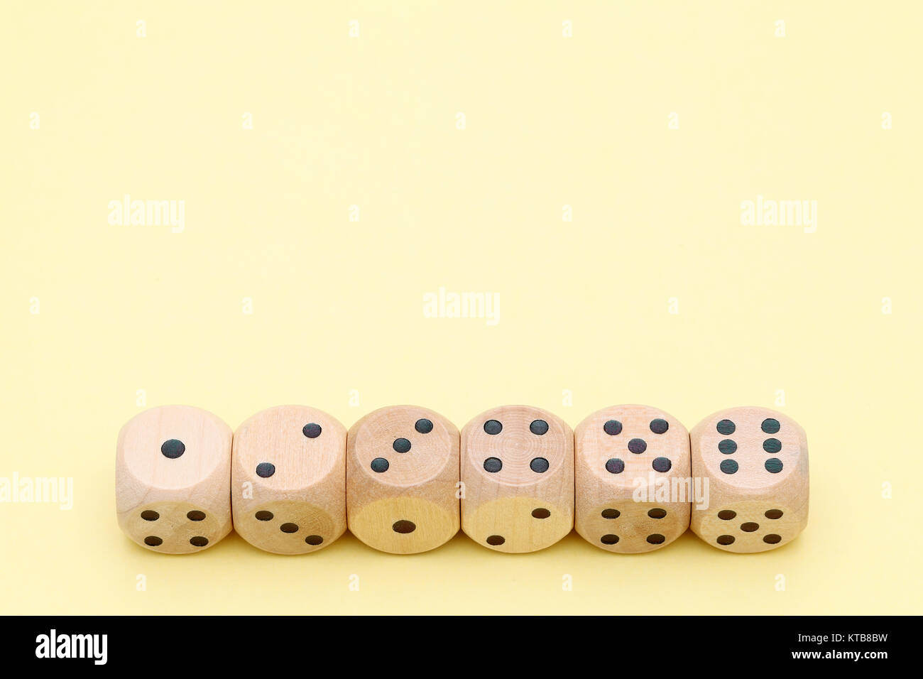 Wooden dice in a row on yellow background Stock Photo - Alamy