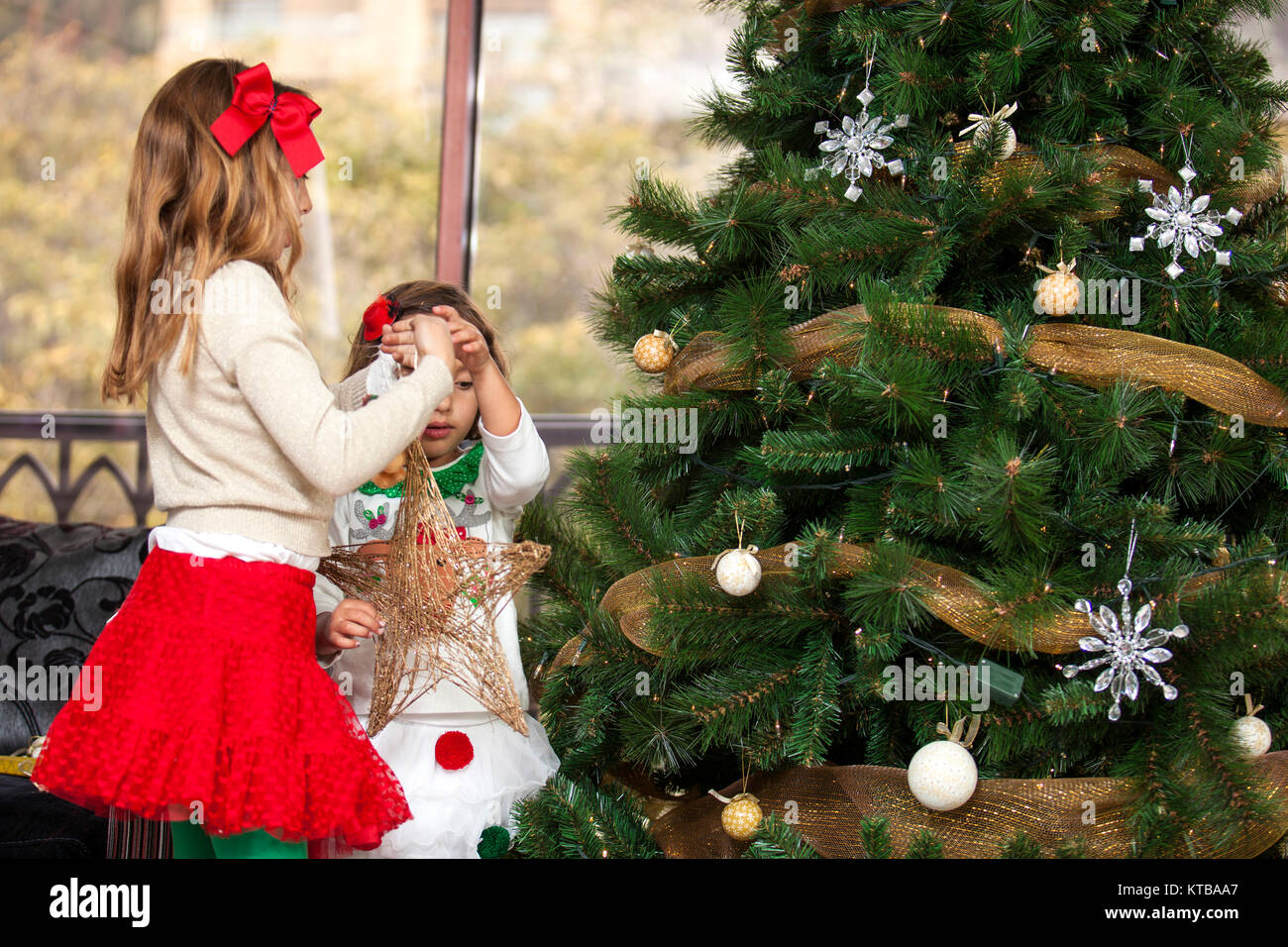 Sisters decorating the Christmas tree Stock Photo - Alamy